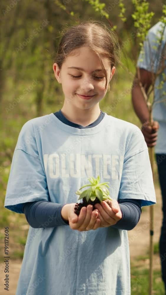 Cute child activist presenting a small seedling tree in her hands ...