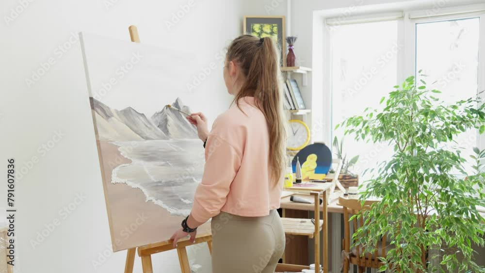 Young woman artist drawing picture on canvas using acrylic paints ...