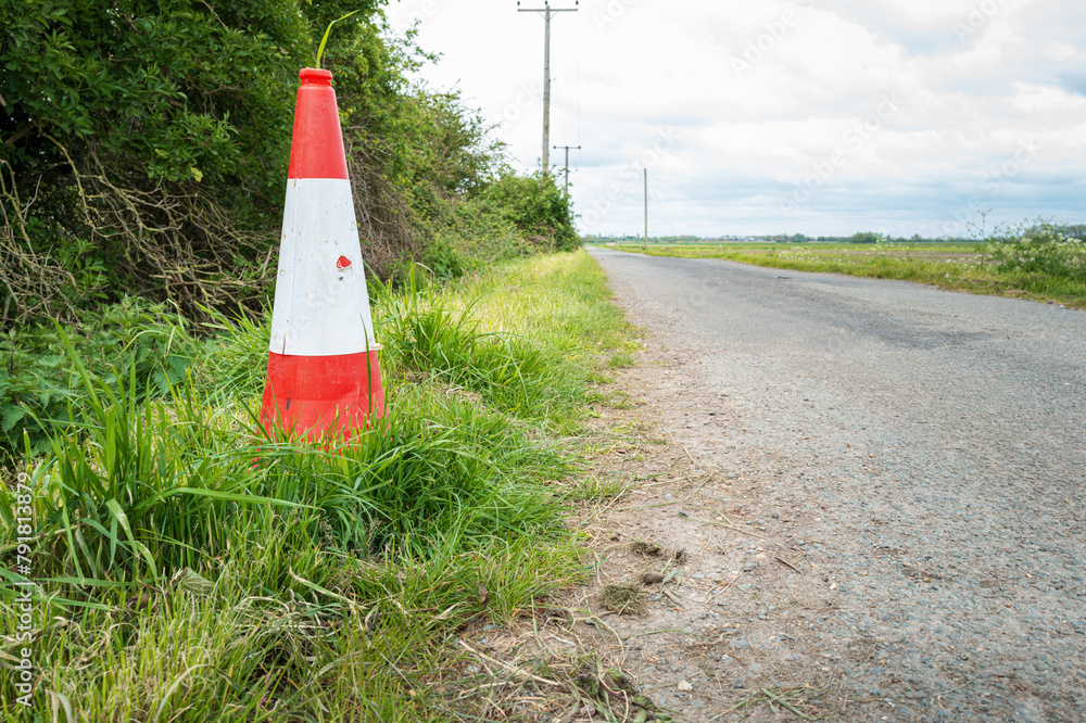 Isolated traffic cone seen near the entrance to a sewage works, located ...