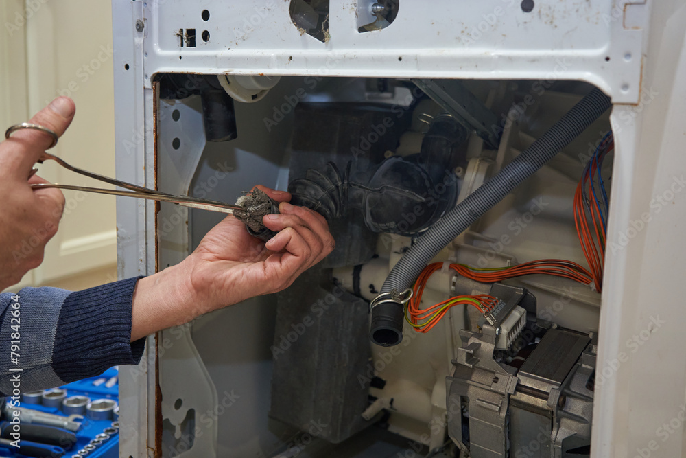 clogged hose in the washing machine, repairing a washing machine, a man ...
