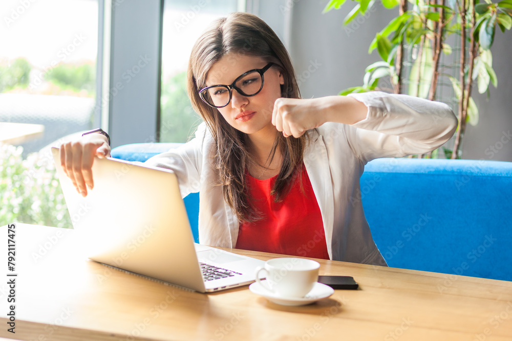 Portrait of angry woman working on laptop arguing showing fist to ...