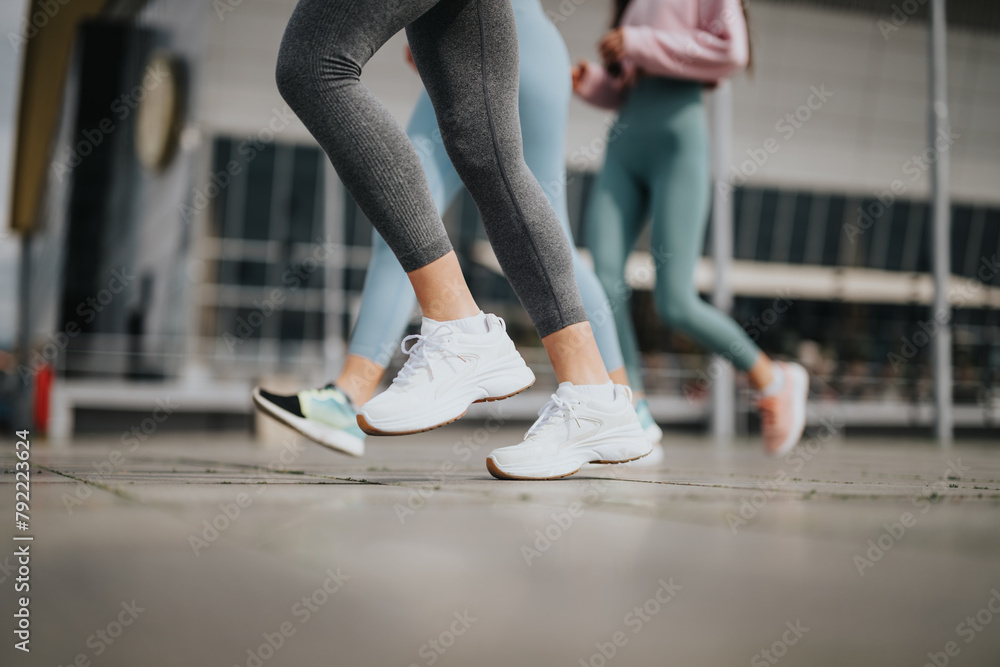 A detailed shot capturing two women's legs in sportswear and sneakers ...