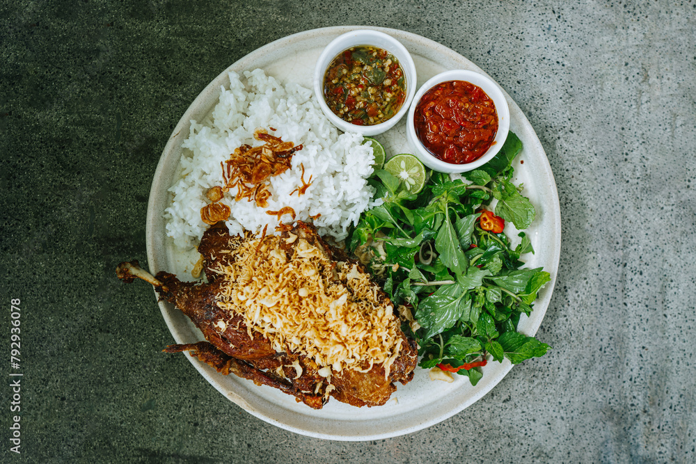Deep fried duck with rice, green vegetables, and two types of sambals ...