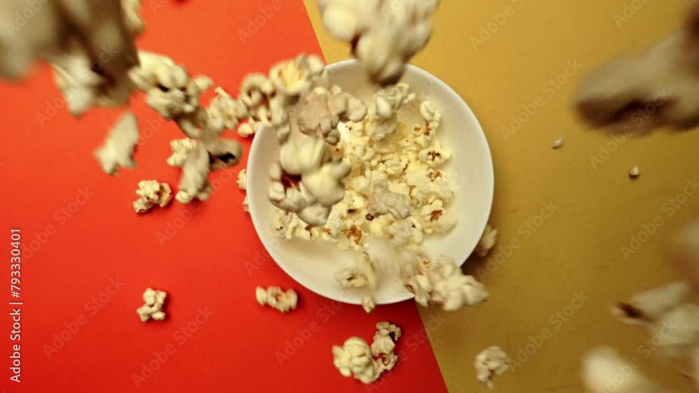Top down view of flying popcorn dropping at white bowl with yellow and ...