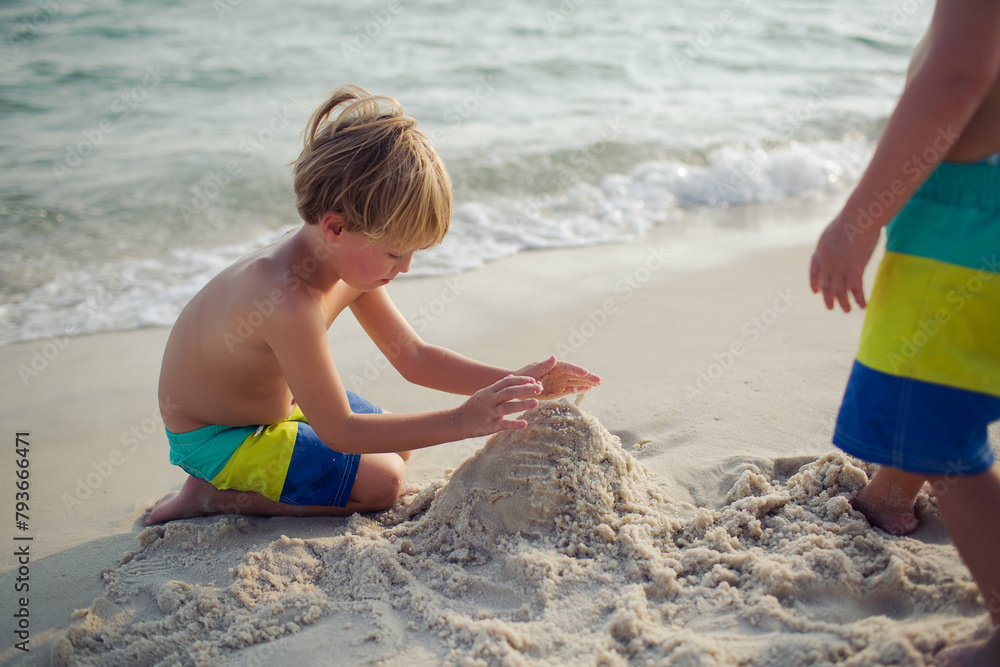Little boy intently crafting a sandcastle by the sea Stock Photo ...