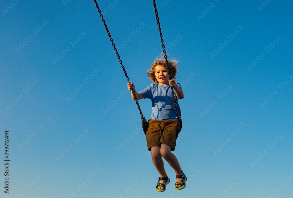 Excited kid swinging on chain swing on city kids playground. Swing ride. Cute child having fun ...