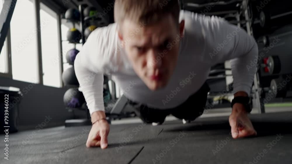 A focused Caucasian male in athletic gear performs push-ups, showcasing ...