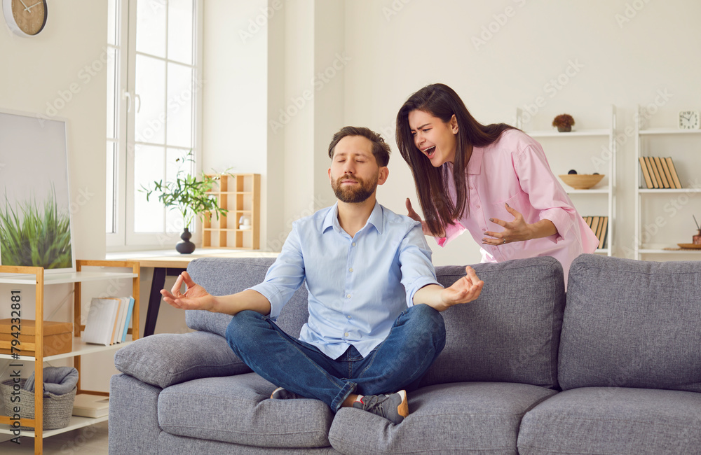 Angry woman quarrels and shouts at man who is sitting in meditative ...