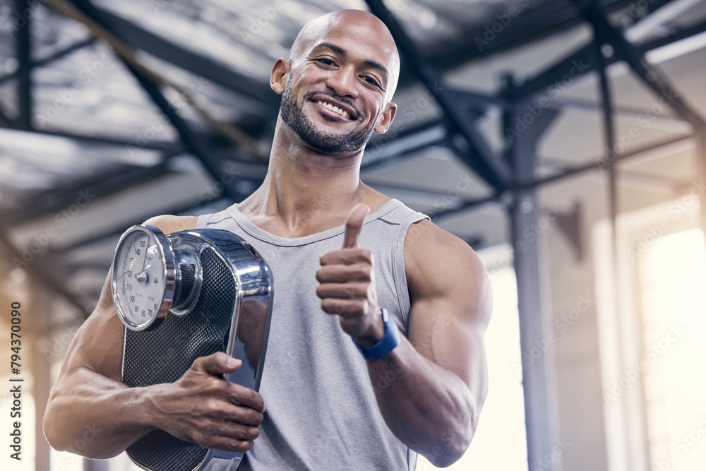 Portrait, scale and thumbs up with bodybuilder man in gym for strength ...
