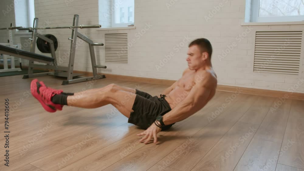Young man is working out in gym and doing crunches and handstand corner ...