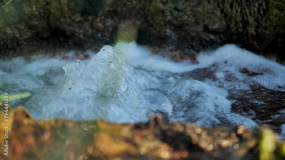 Splashes of a bubbling spring of mineral foamy water in slow motion. A ...
