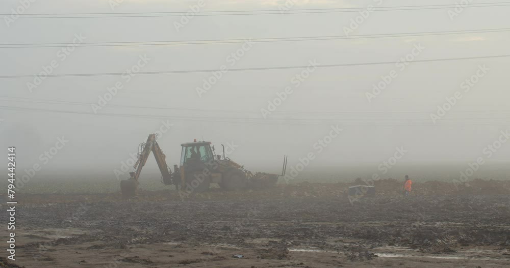 Excavator in a foggy field starts work at the construction site ...