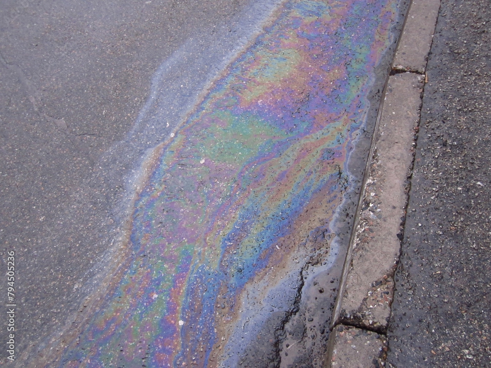 Rainbow colored rain water stream contaminated with gasoline flows ...