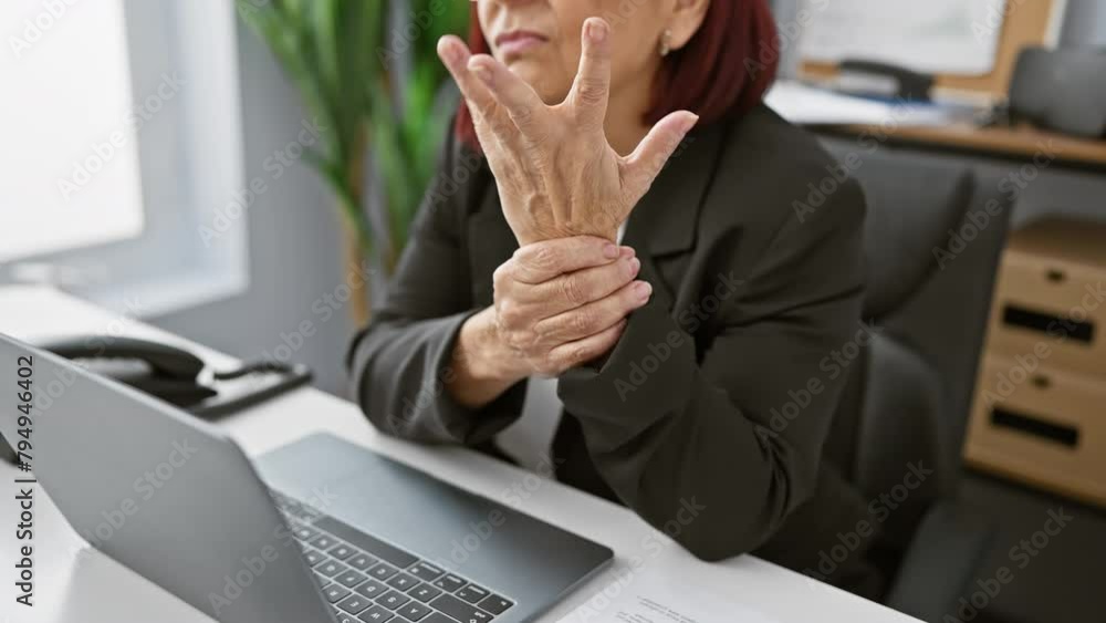 Middle-aged woman experiencing wrist pain at her office desk ...