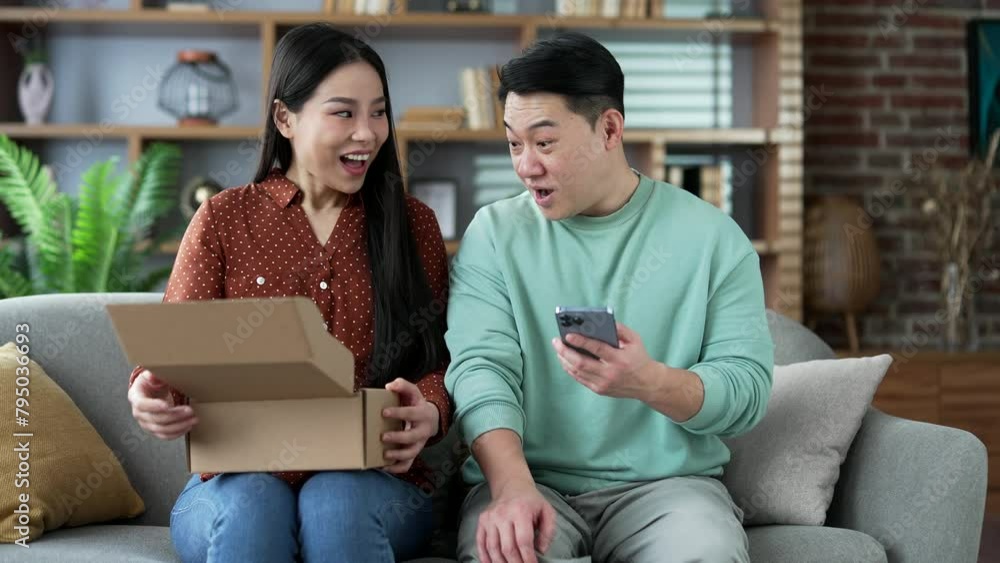 Joyful asian family couple customer opens package at home. Happy wife ...