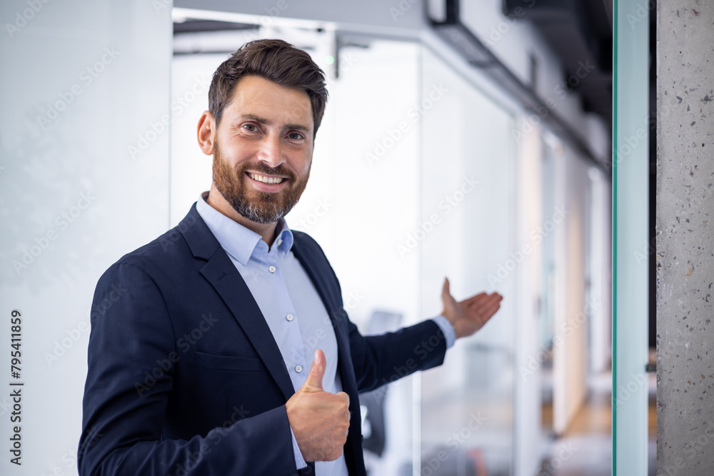 A young smiling male businessman, the founder of the company stands in ...