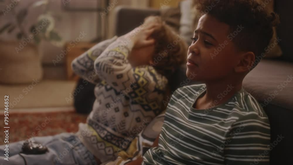 Side tilt handheld footage of diverse kids losing TV console video game ...