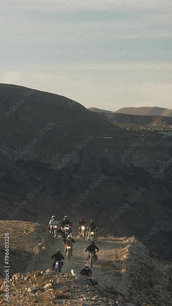This vertical frame captures a group of motorcyclists riding in ...