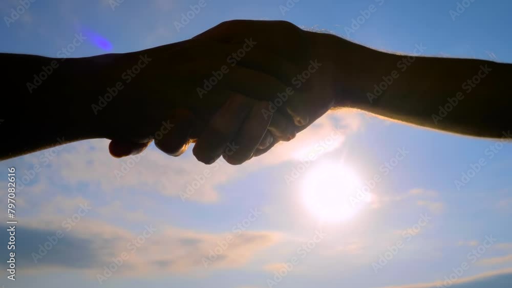 Close up: man and woman silhouettes are shaking hands against the ...