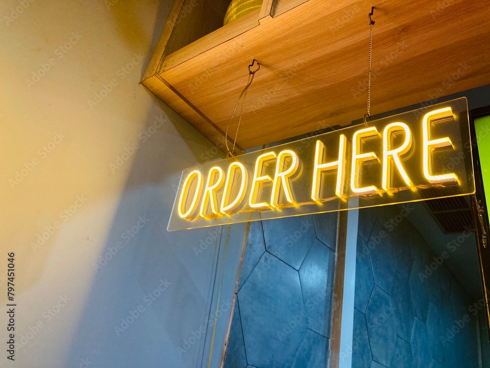 Glowing Order here sign hanging on the ceiling, business signpost ...