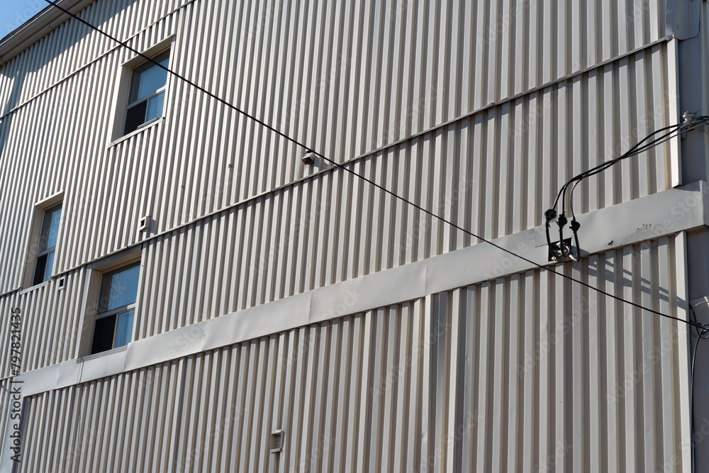 side of a building clad in corrugated sheet metal with wires and window ...