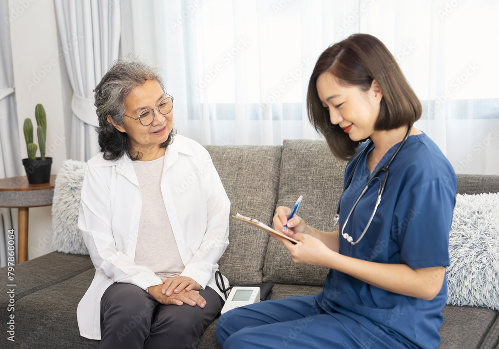 A senior woman giving a health interview to a home visiting nurse, a ...