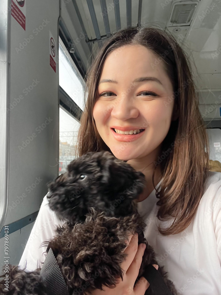 Cute Korean woman holding black poodle puppy in arms and smiling ...
