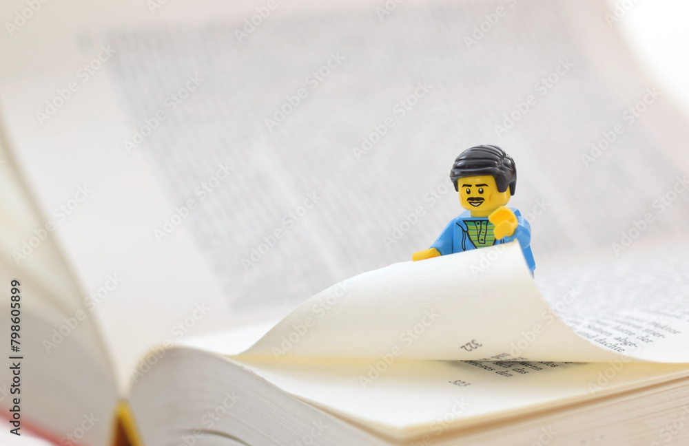 Lego minifigure of cute man is turning a page in book. Concept image to ...