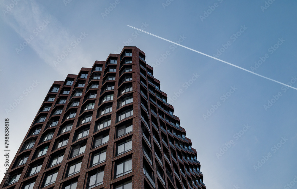 A trace of a passing plane over a modern multi-storey business class ...