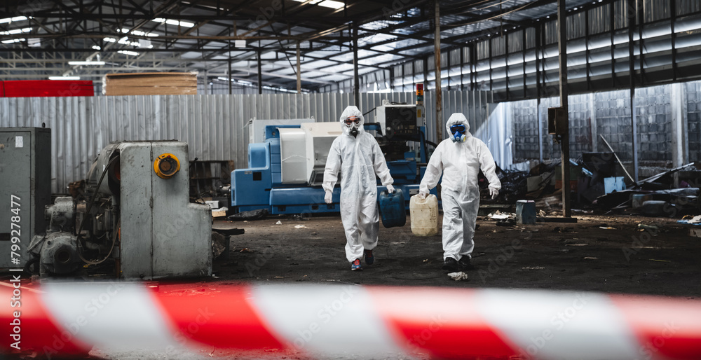 Workers in protective suits inspect chemicals in an old factory ...