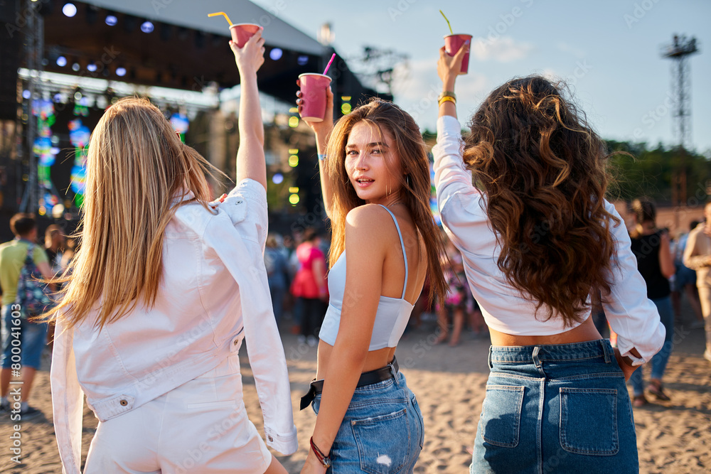 Group of female friends enjoy summer music festival on sandy beach ...