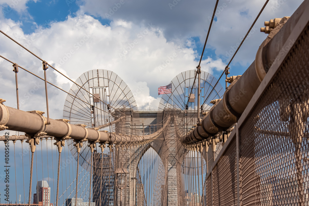 The gate of Brooklyn Bridge with a waving American flag on top of it ...