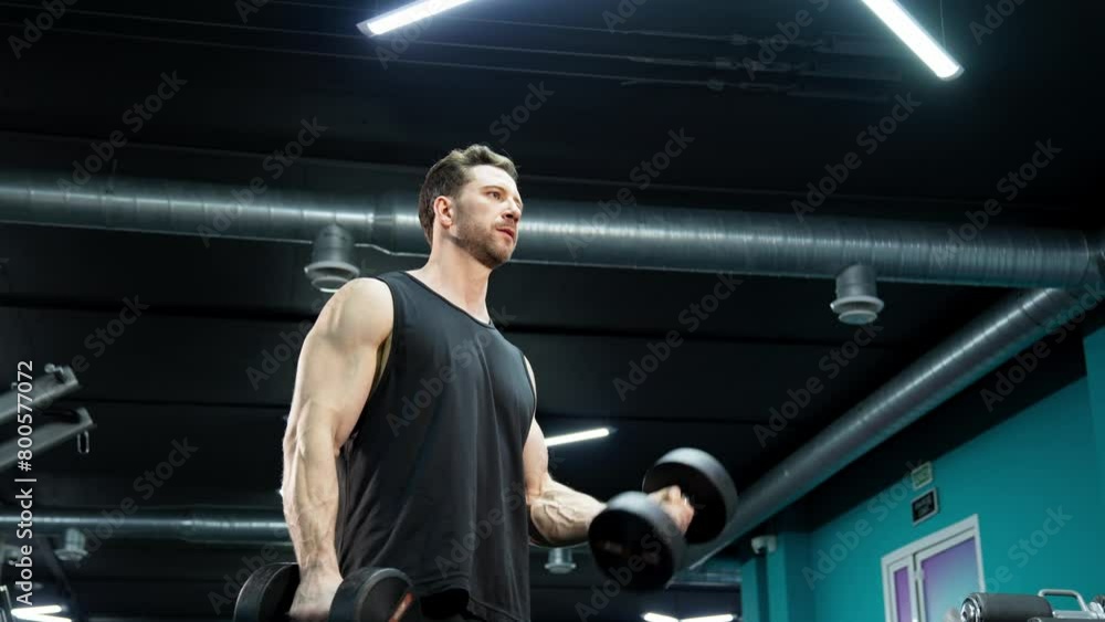 Bodybuilder lifting heavy black dumbbells in modern gym. Handsome ...
