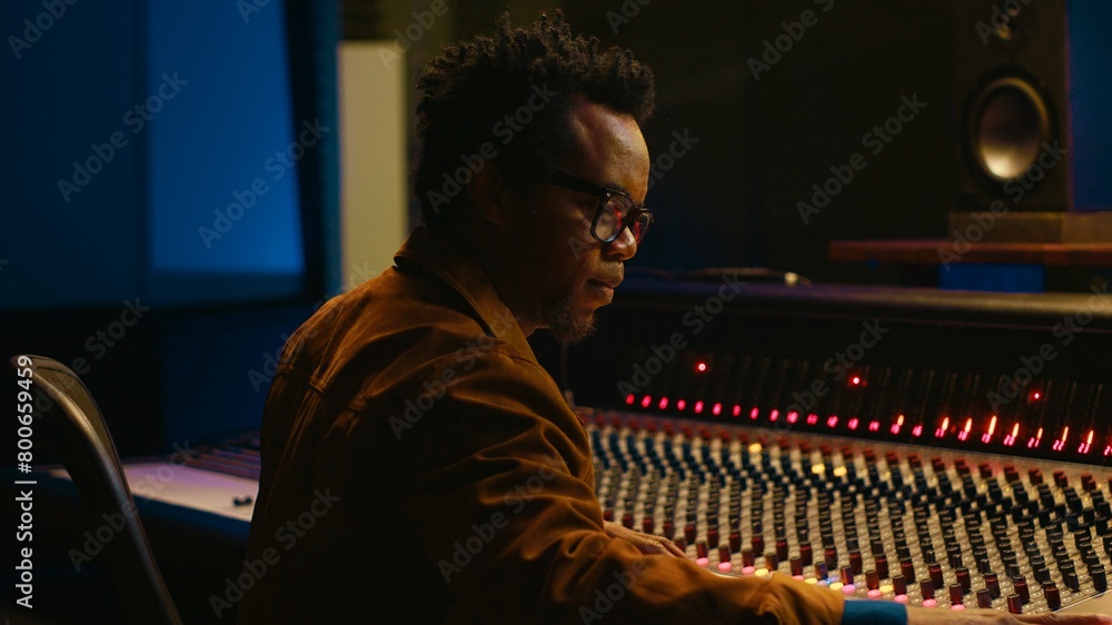 Portrait of african american audio technician uses mixing console with ...