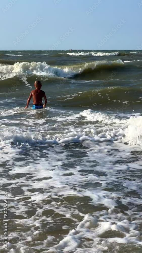 A child swims in the Sea of Azov. A boy jumps into the sea waves from ...