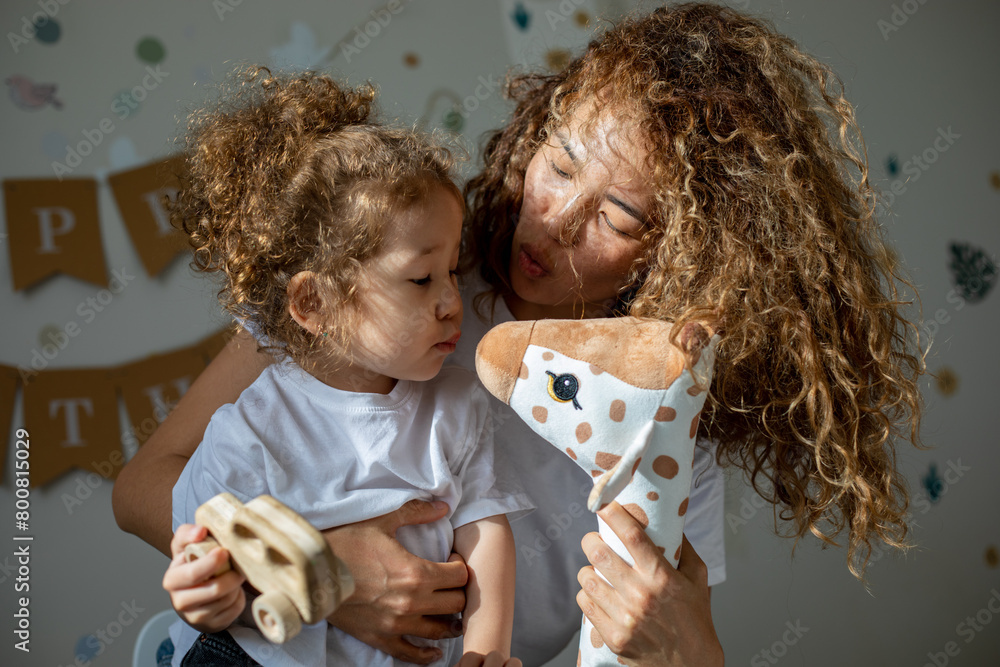 Curly mother and child play against the background of the inscription ...