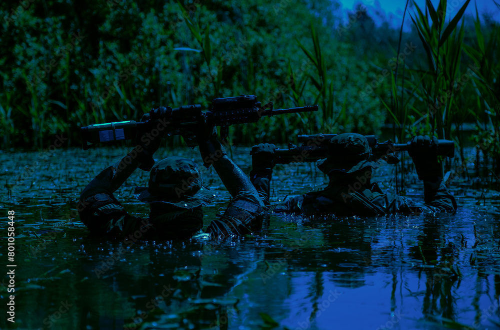 Soldiers move in the heart of a marsh, submerged in swampy waters with ...