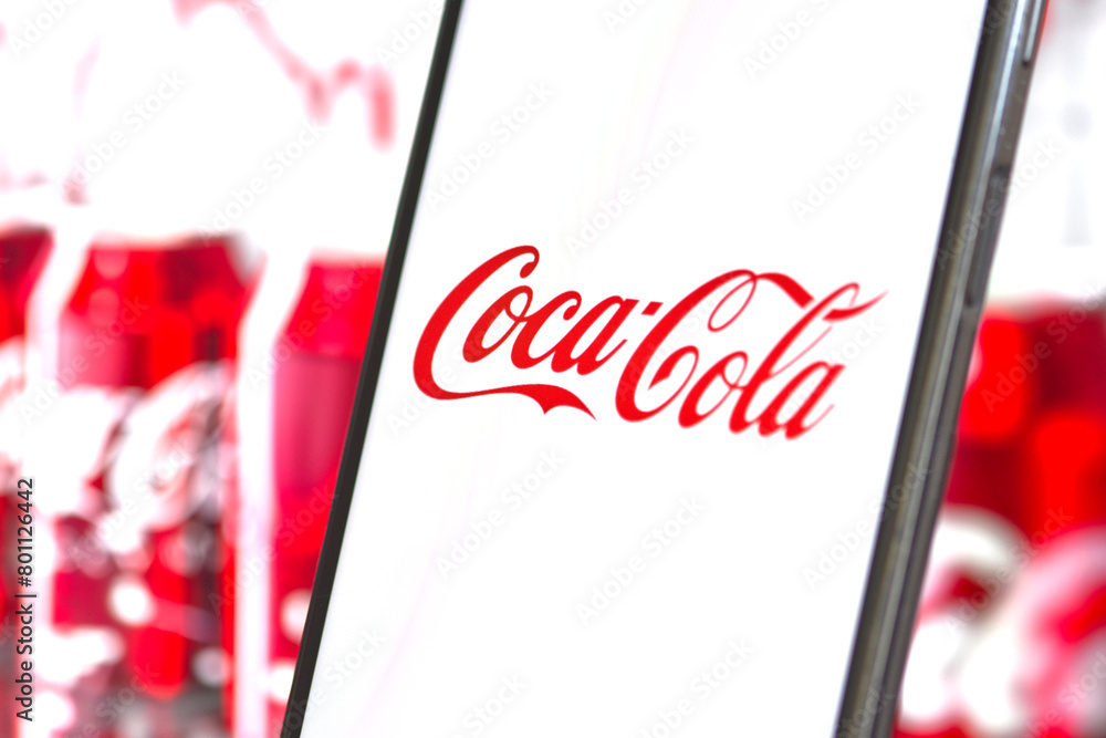 Coca-Cola company logo on screen of smartphone against blurred ...