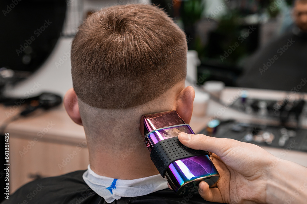 Hairstylist removes hair behind client ear and occiput with shaver in ...