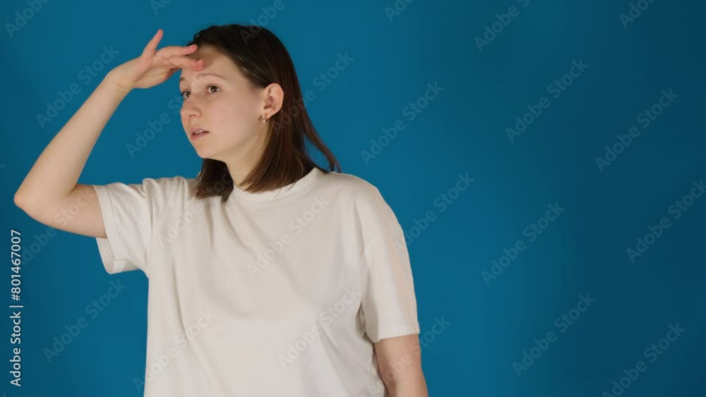 Lady puts hand to forehead as searching on blue background. Woman scans ...