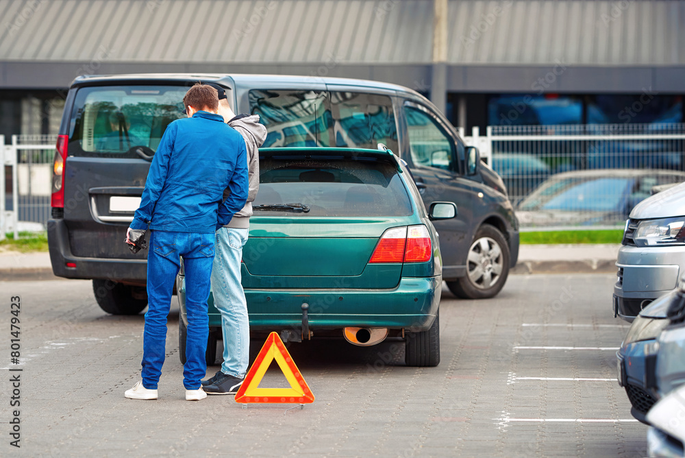 Car accident in parking lot, men set up red warning triangle after ...