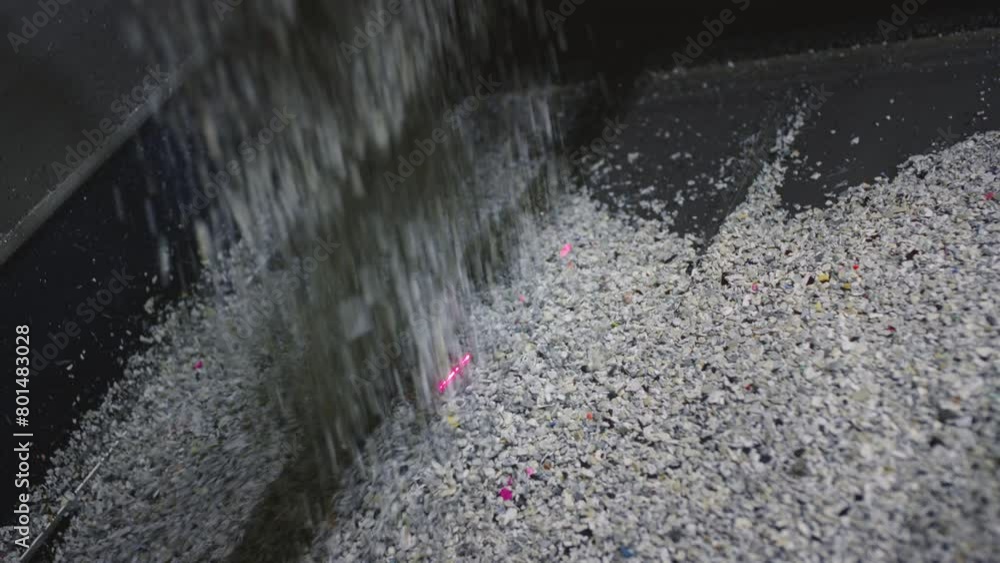 Plastic particles fall onto a conveyor belt, scanned by a laser ...
