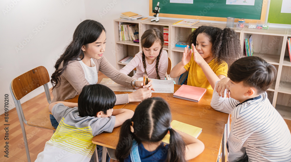 Pupils group study with teacher in classroom at elementary school ...