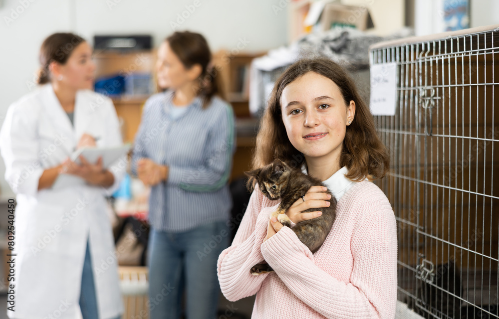 Cheerful cute tween girl standing near cages for homeless animals in ...