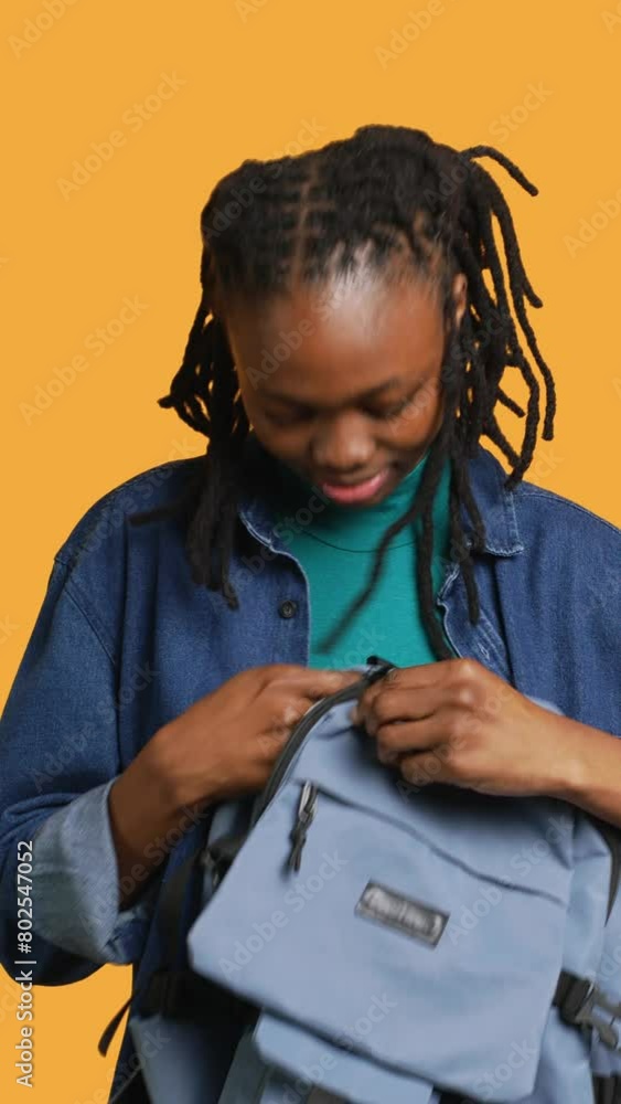 Vertical video Portrait of upbeat woman searching through backpack ...