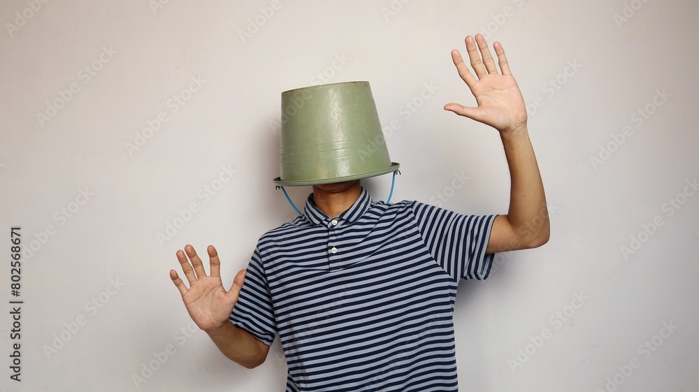 young man using a bucket on his head on a white background. showing ...