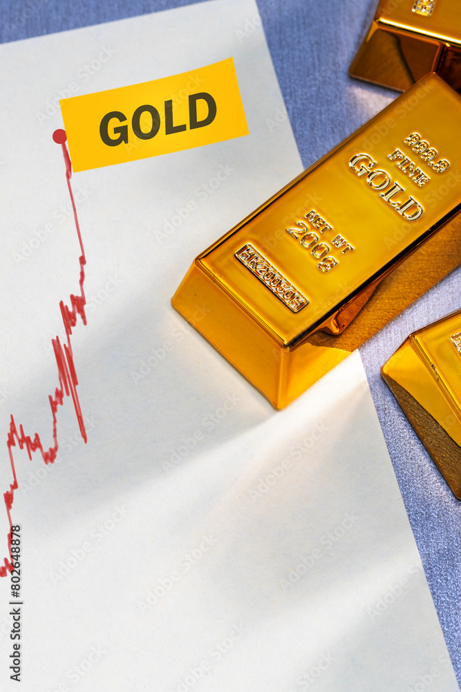 Gold value. Rising chart of price of gold and gold bars on the desk ...