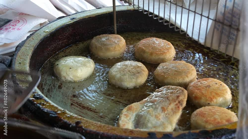 Delicious Xian Bing cooking in the pan, a stall vendor flipping savoury ...