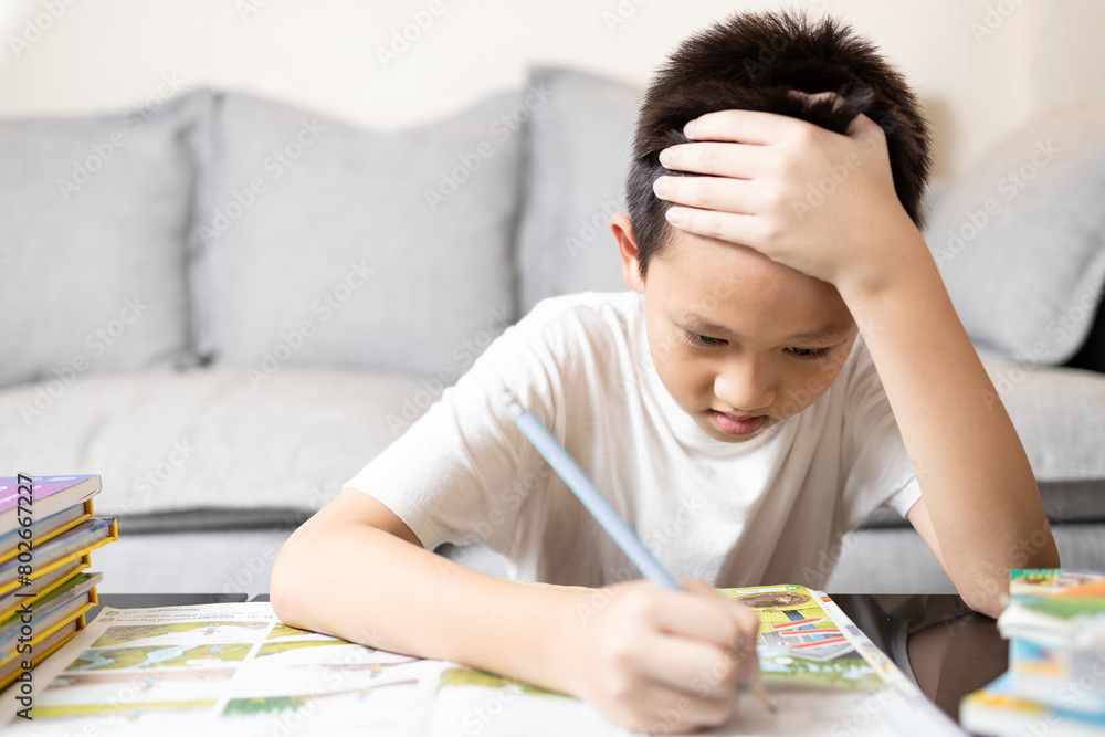 Stressed kid boy holding his head while doing homework,tired from ...
