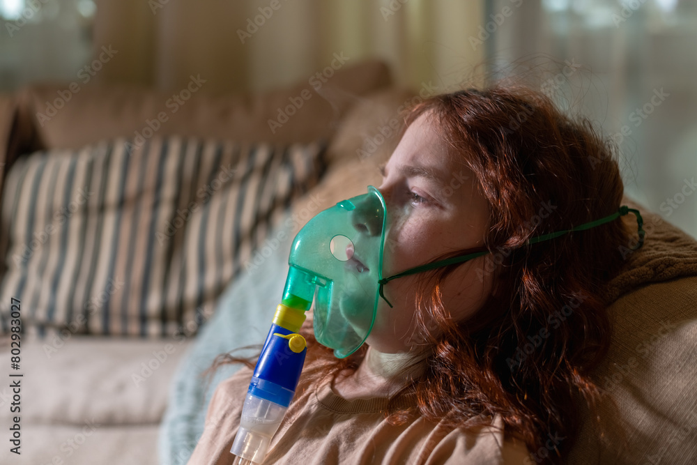 Sick girl making inhalation with nebulizer to reduce coughing, at home ...